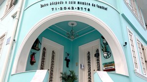 Um edifício azul-turquesa com uma placa que diz "Entre Hospede e Sala Membro da Familia" e um número de telefone.
