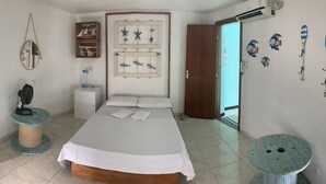 Quarto com cama, uma mesinha com abajur, espelho e decorações nas paredes.