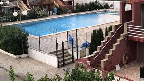 Piscina cercada por uma grade, com escadas que dão acesso à área da piscina.