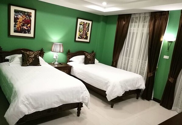 Quarto de hotel com duas camas, paredes verdes e obras de arte.