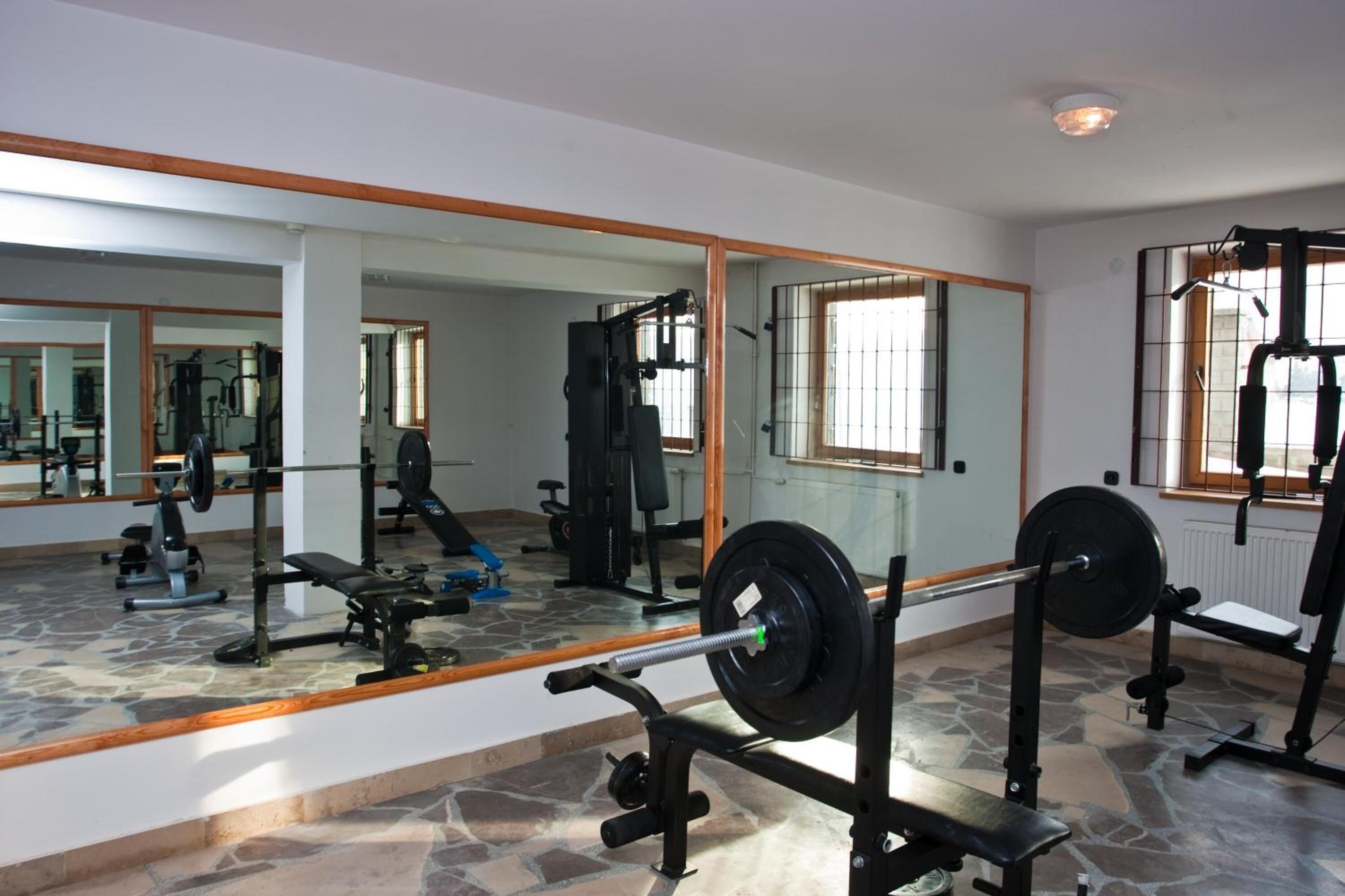 Uma academia com equipamentos de exercício, um espelho grande e piso de ladrilho.