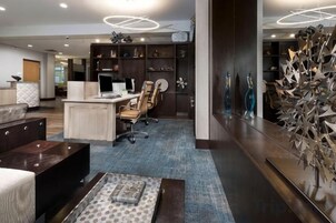 Um espaço de escritório moderno com balcão de recepção, posto de computador e área de estar com tapete estampado.