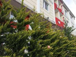 Um edifício com fachada vermelha e branca, varandas e uma janela com decoração metálica circular.