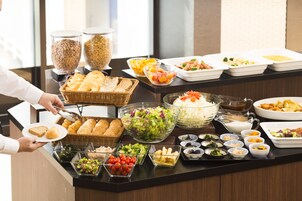Buffet com diversos alimentos, incluindo pão, saladas e outros pratos.