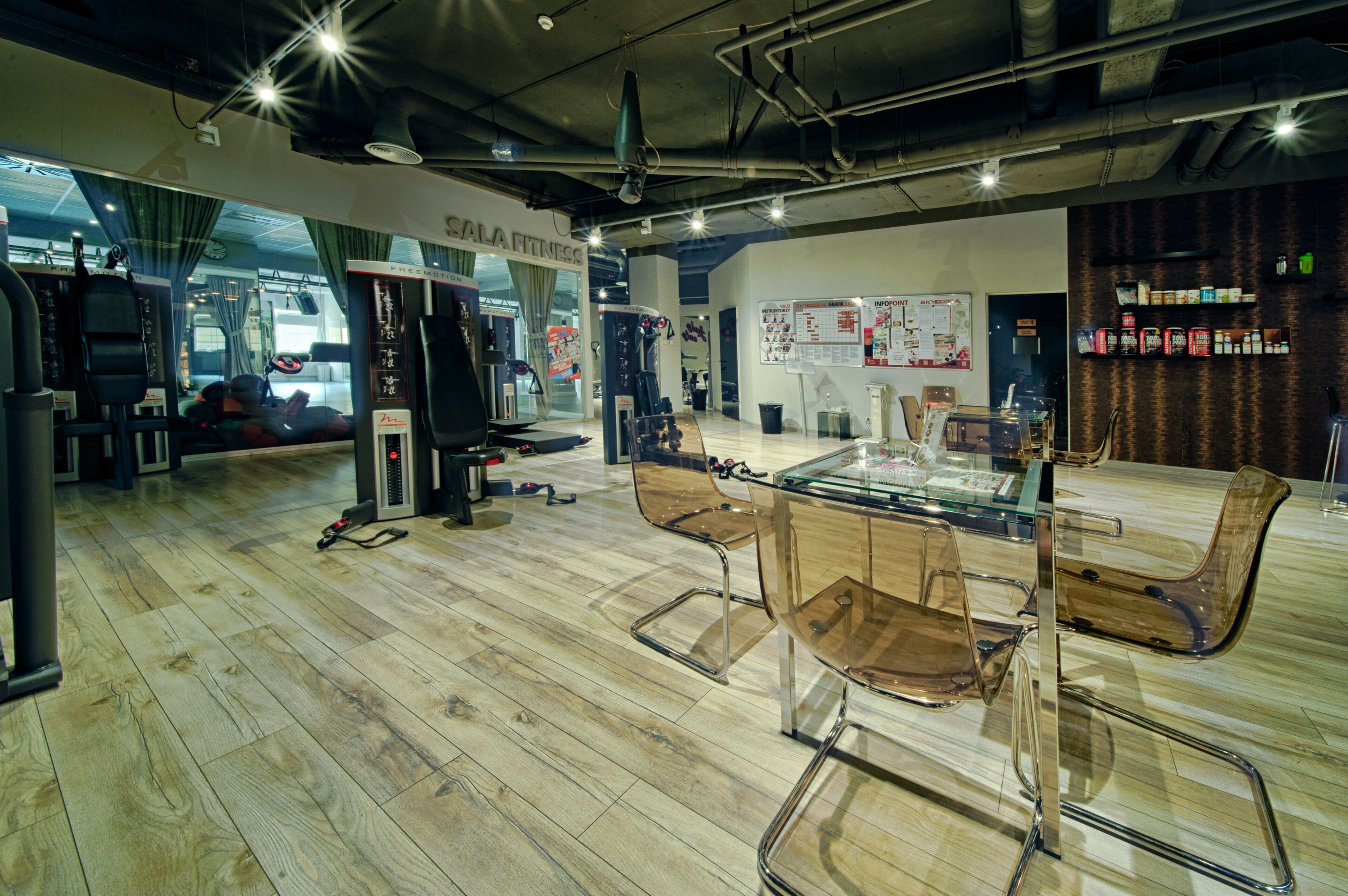Um centro de fitness moderno com equipamentos de exercício, uma mesa de vidro e cadeiras.