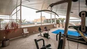 Uma academia com equipamentos de ginástica, um tapete azul e uma cadeira.