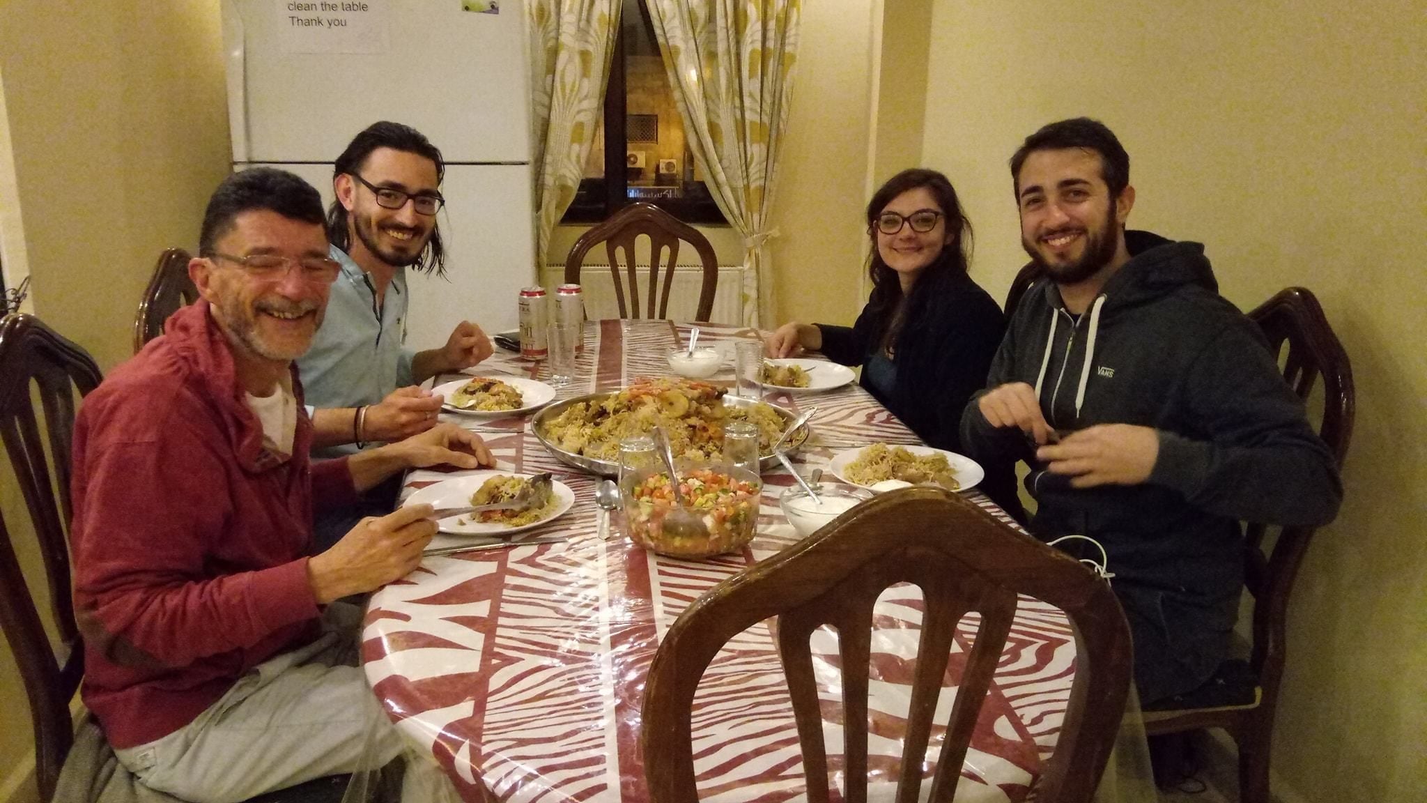 Um grupo de pessoas jantando à mesa com toalha de mesa listrada em preto e branco.