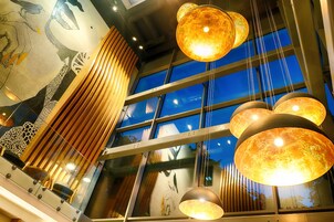 Um interior moderno com grandes janelas, ripas de madeira e luminárias esféricas penduradas.