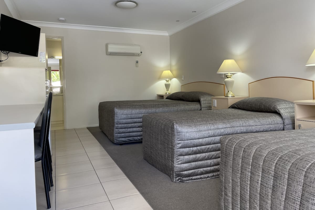 Quarto de hotel com duas camas, televisão e ar condicionado.