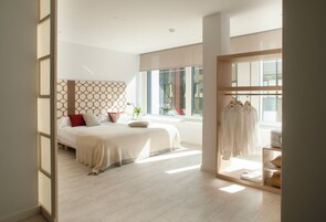 Quarto moderno com uma cama grande, um guarda-roupa e uma janela com vista para a cidade.