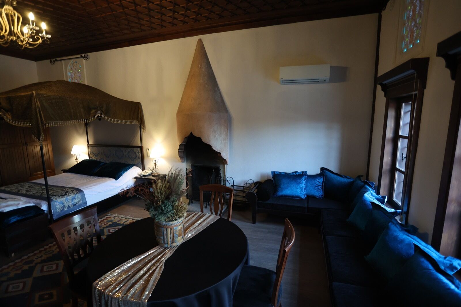 Um quarto com cama, sofá, mesa com um vaso e lareira.