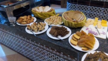 Buffet com diversos itens, incluindo doces, sanduíches e sobremesas.