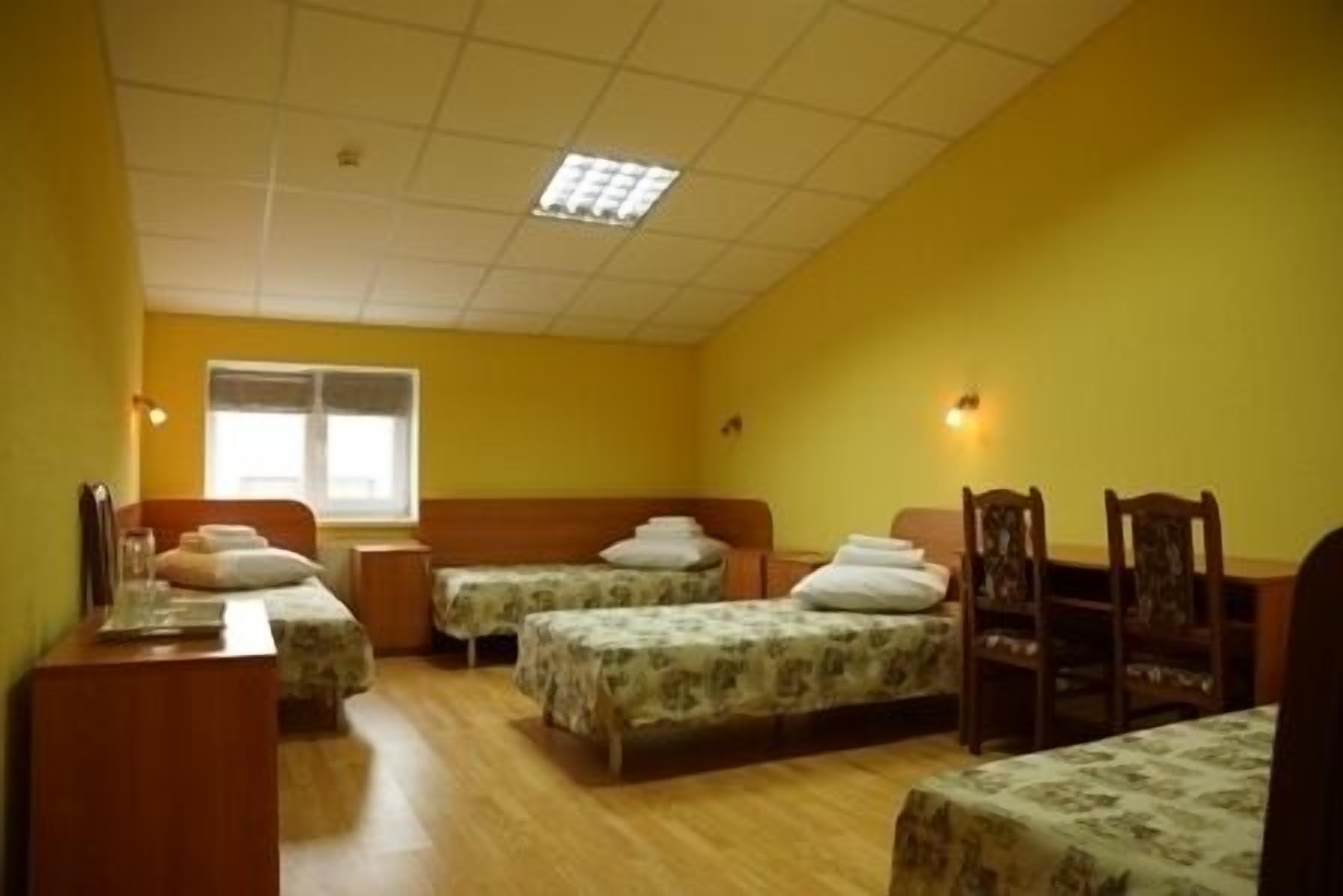 Quarto com duas camas de solteiro, uma escrivaninha de madeira e uma cadeira.
