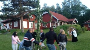 Um grupo de pessoas caminhando em uma área gramada, com um edifício vermelho ao fundo.
