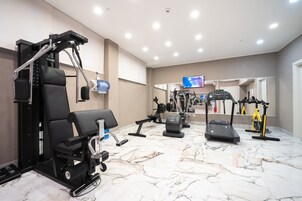 Uma academia com diversos equipamentos de exercício, incluindo uma máquina de musculação, esteiras e bicicletas ergométricas.