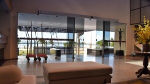Um interior moderno com uma ampla parede de vidro, um banco de madeira e uma mesa com um vaso de flores.