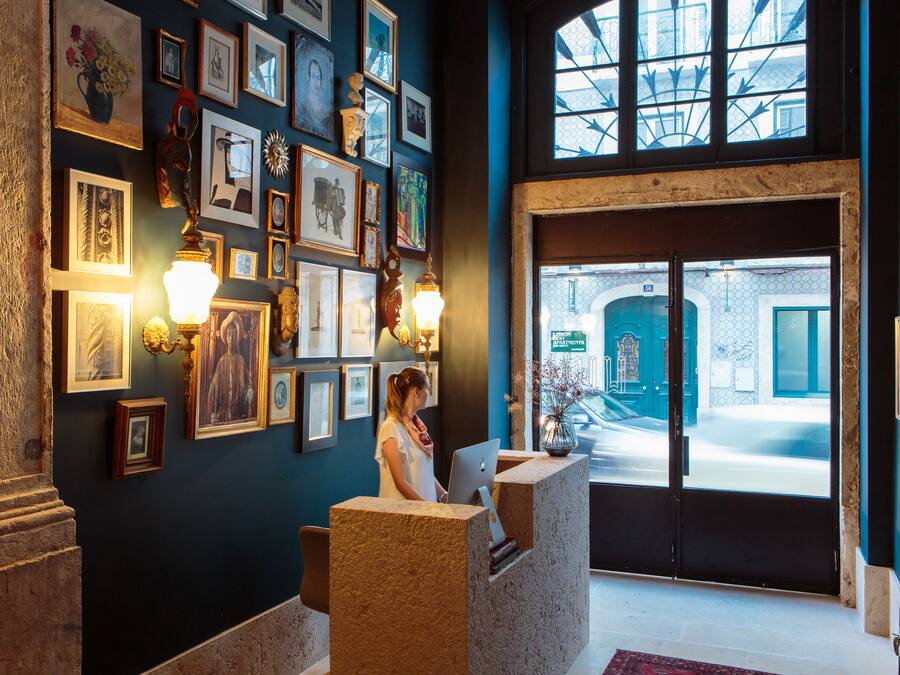 Uma área de recepção com recepcionista em um balcão, obras de arte emolduradas nas paredes e vista da rua através de uma grande janela.