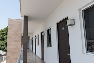 Um edifício moderno com um corredor longo, portas numeradas 112 e uma varanda com guarda-corpo.