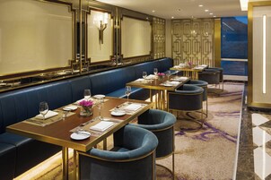 Um restaurante com um longo banco azul, várias mesas e cadeiras.