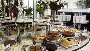 Buffet com diversos alimentos e vitrine de vidro.