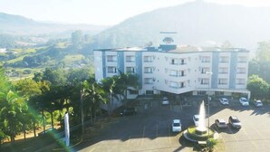 Hotel de vários andares com um pátio central, rodeado por vegetação exuberante e paisagens montanhosas.