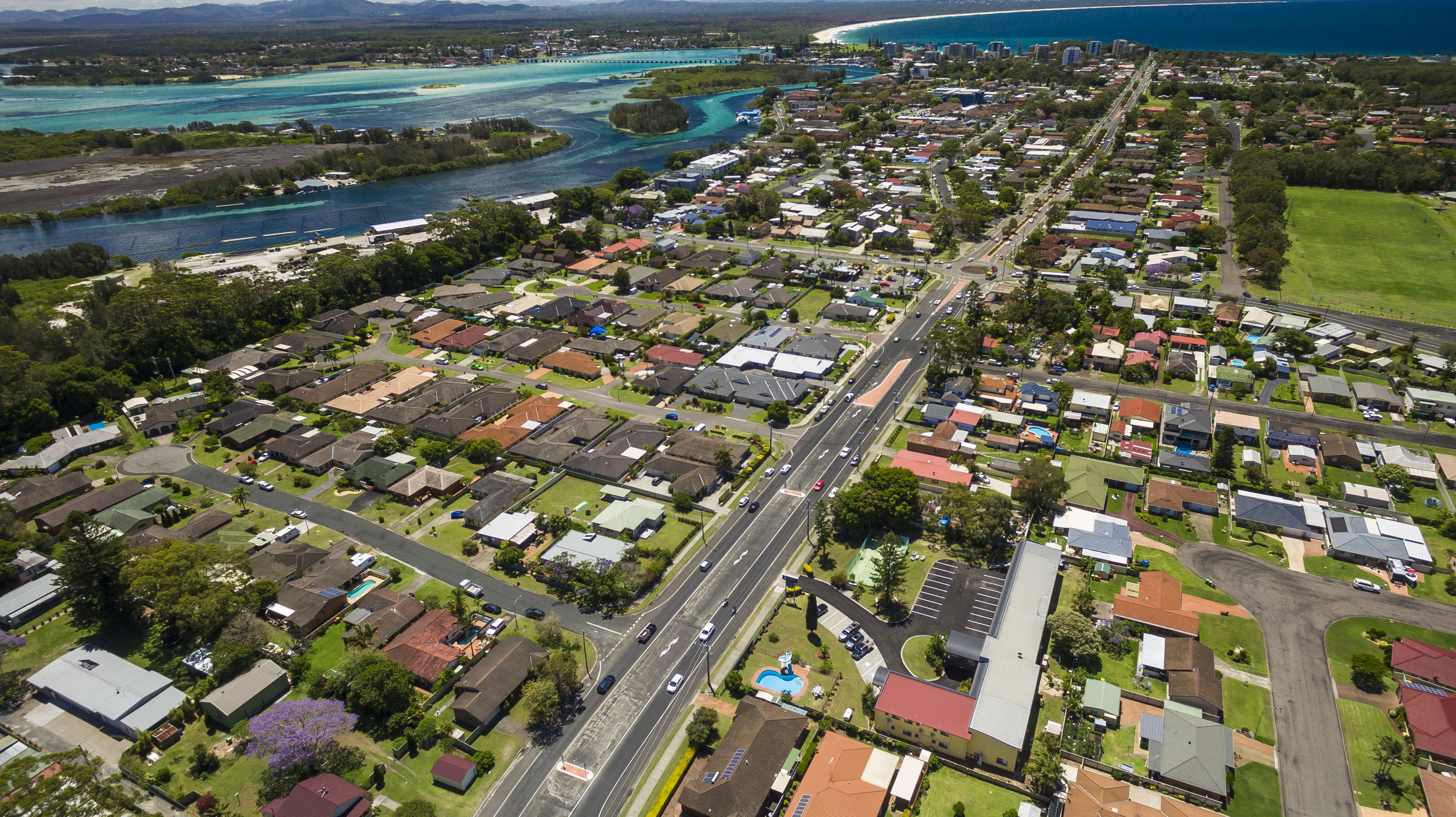 Vista aérea de uma área residencial com casas, ruas e uma orla marítima.