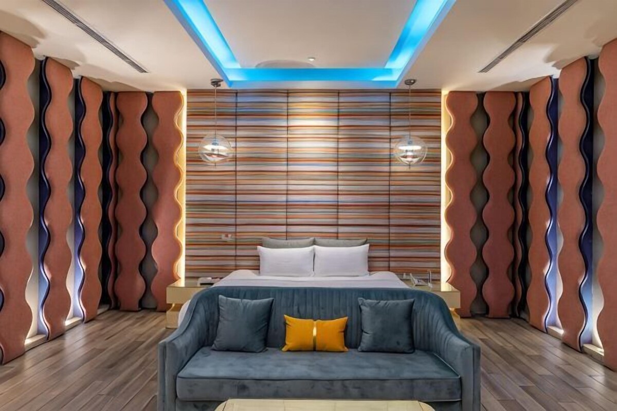 Quarto moderno com cama, sofá e um design de parede ondulado único.