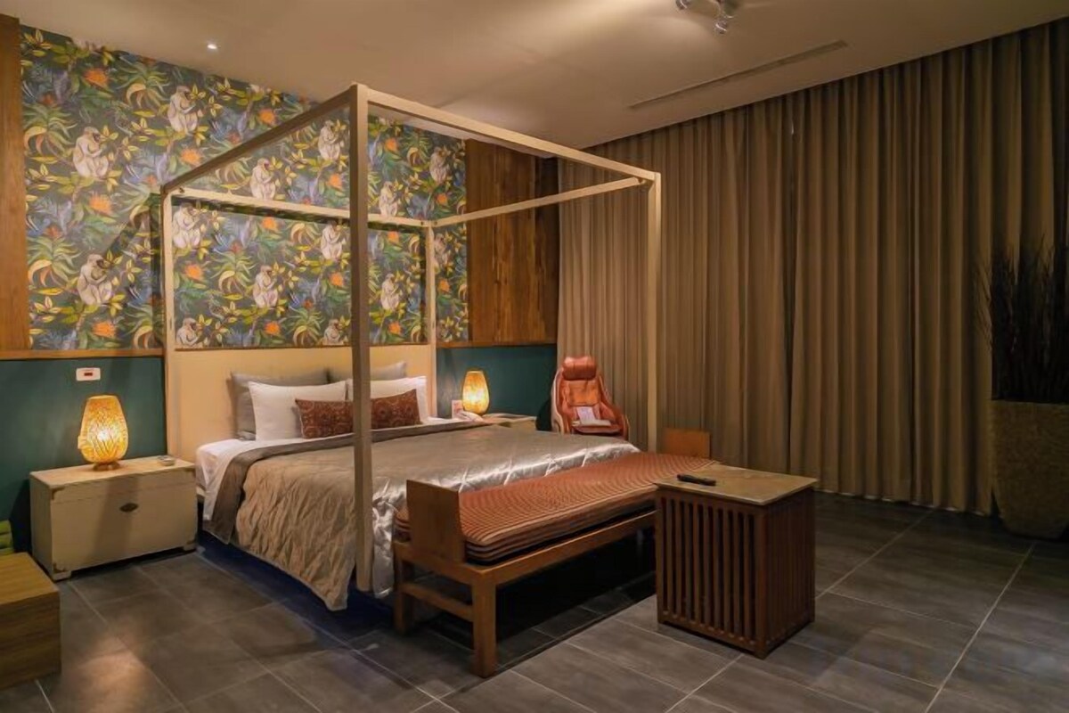 Uma cama com dossel e cortina, mesa de cabeceira, um banco e uma mesinha de noite.