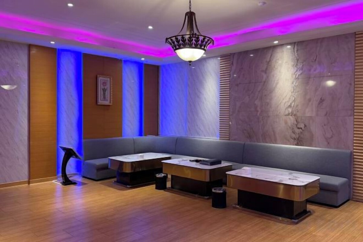 Uma área de estar moderna com sofá, duas mesinhas de centro e luminária pendente.