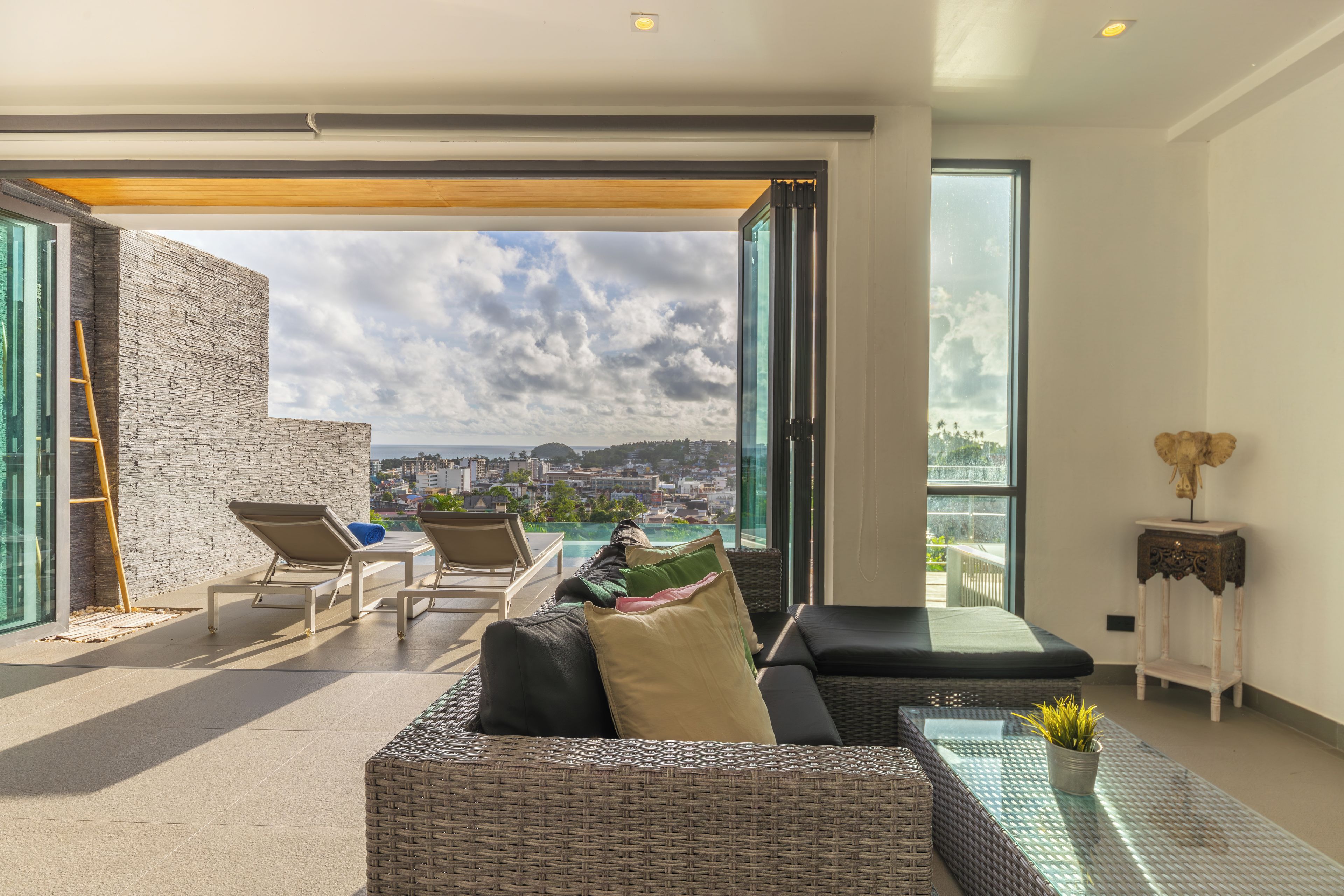Uma sala de estar moderna com vista para a paisagem urbana, uma varanda com porta de vidro e uma parede de pedra.