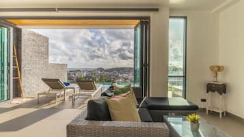 Uma sala de estar moderna com vista para a paisagem urbana, uma varanda com porta de vidro e uma parede de pedra.