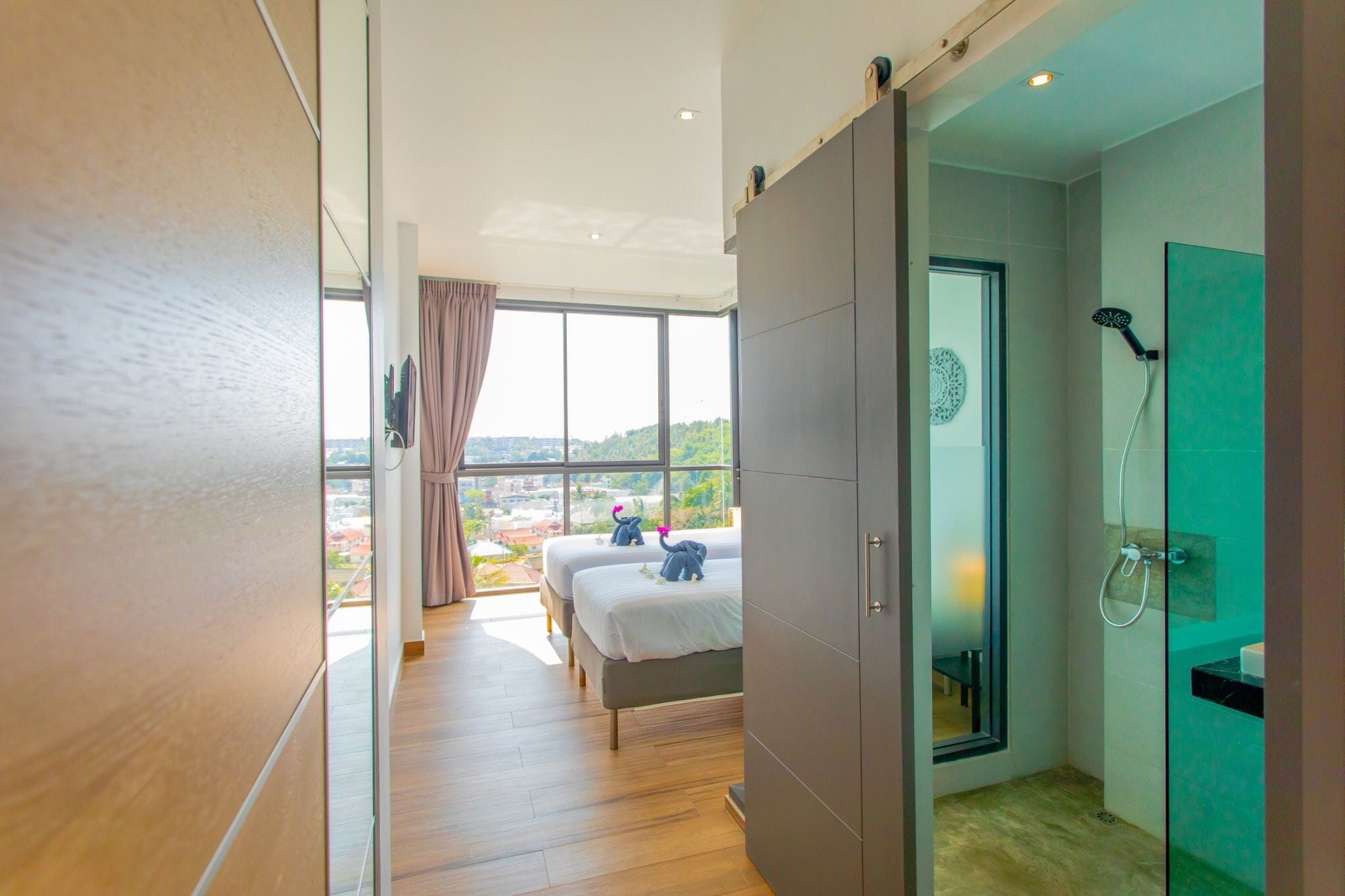 Quarto de hotel com varanda, duas camas, chuveiro e vista para a cidade.