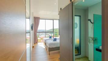 Quarto de hotel com varanda, duas camas, chuveiro e vista para a cidade.