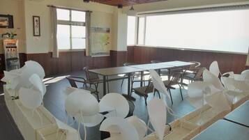 Uma sala de conferências com uma mesa comprida, cadeiras e teto de ripas de madeira.