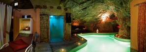 Um spa com cenário de gruta natural, uma porta azul e uma piscina.