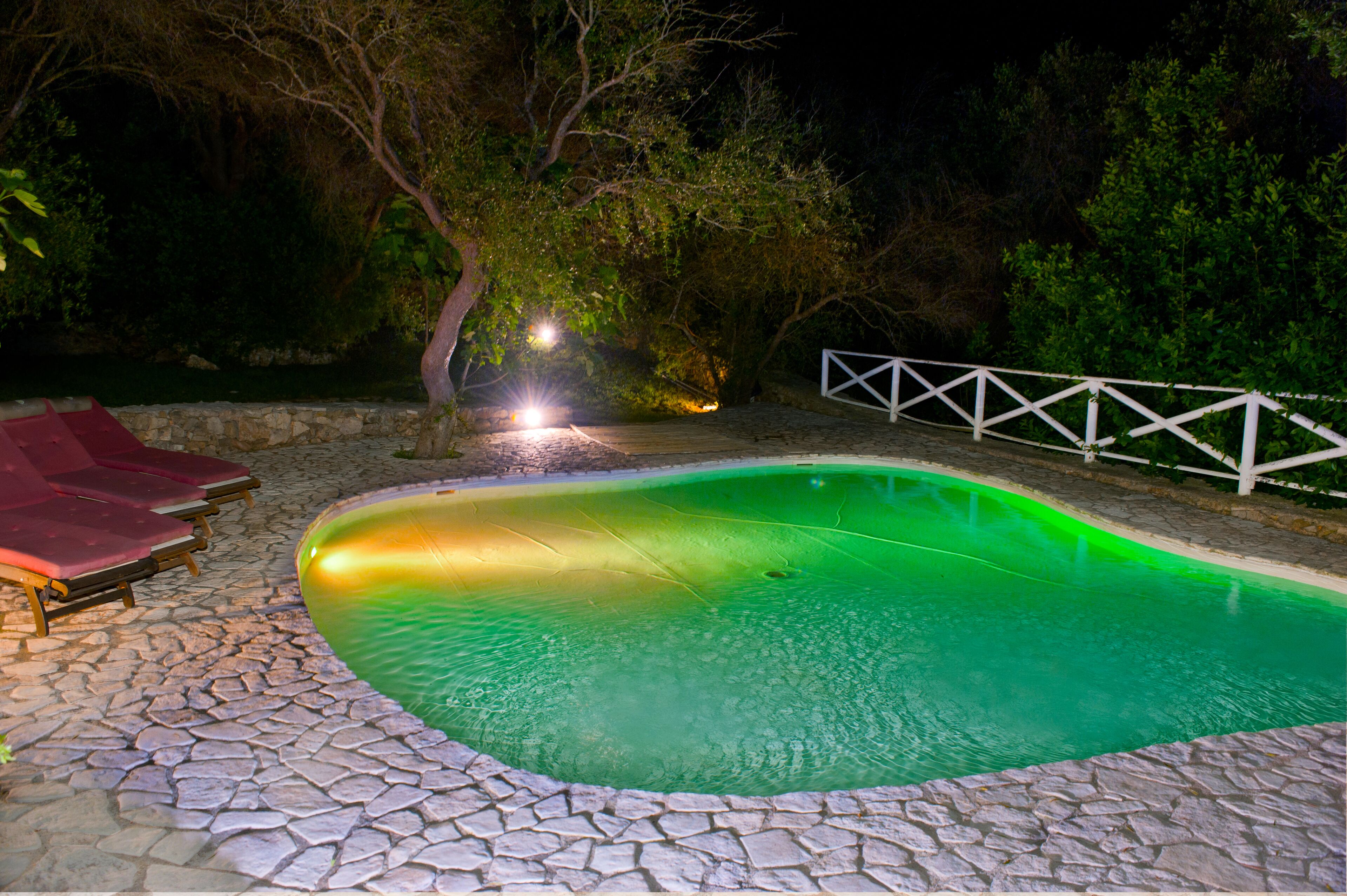 Piscina com deck de ladrilho e cerca branca.