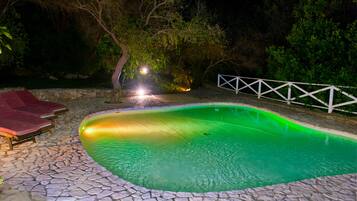 Piscina com deck de ladrilho e cerca branca.
