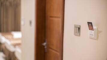 Corredor de hotel com porta de madeira, interruptor de luz e porta-cartões com um cartão.