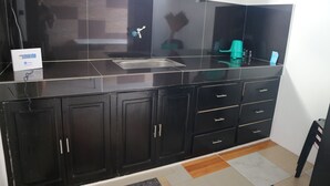 Uma cozinha moderna com armários pretos, uma pia de aço inoxidável e um painel de azulejos.