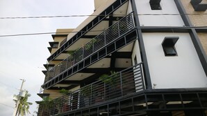 Um edifício com várias andares e varandas, algumas com plantas.