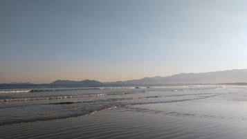 Uma praia com ondas calmas e montanhas ao longe.