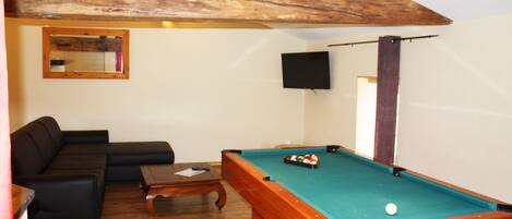 Quarto com mesa de bilhar, sofá e televisão.