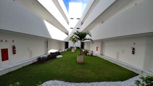Um edifício moderno com um pátio central, paredes brancas e um gramado bem cuidado.