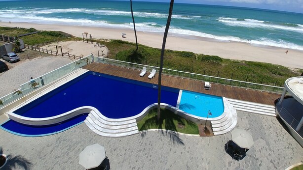 Área da piscina com vista para a praia e o oceano.