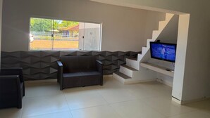 Uma sala de estar moderna com um sofá, uma televisão e uma escada.