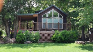 Uma cabana com varanda coberta, um deck e uma placa que diz 'Pecan Cabin'.