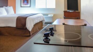 Quarto de hotel moderno com cama, televisão de tela plana e fogão embutido.