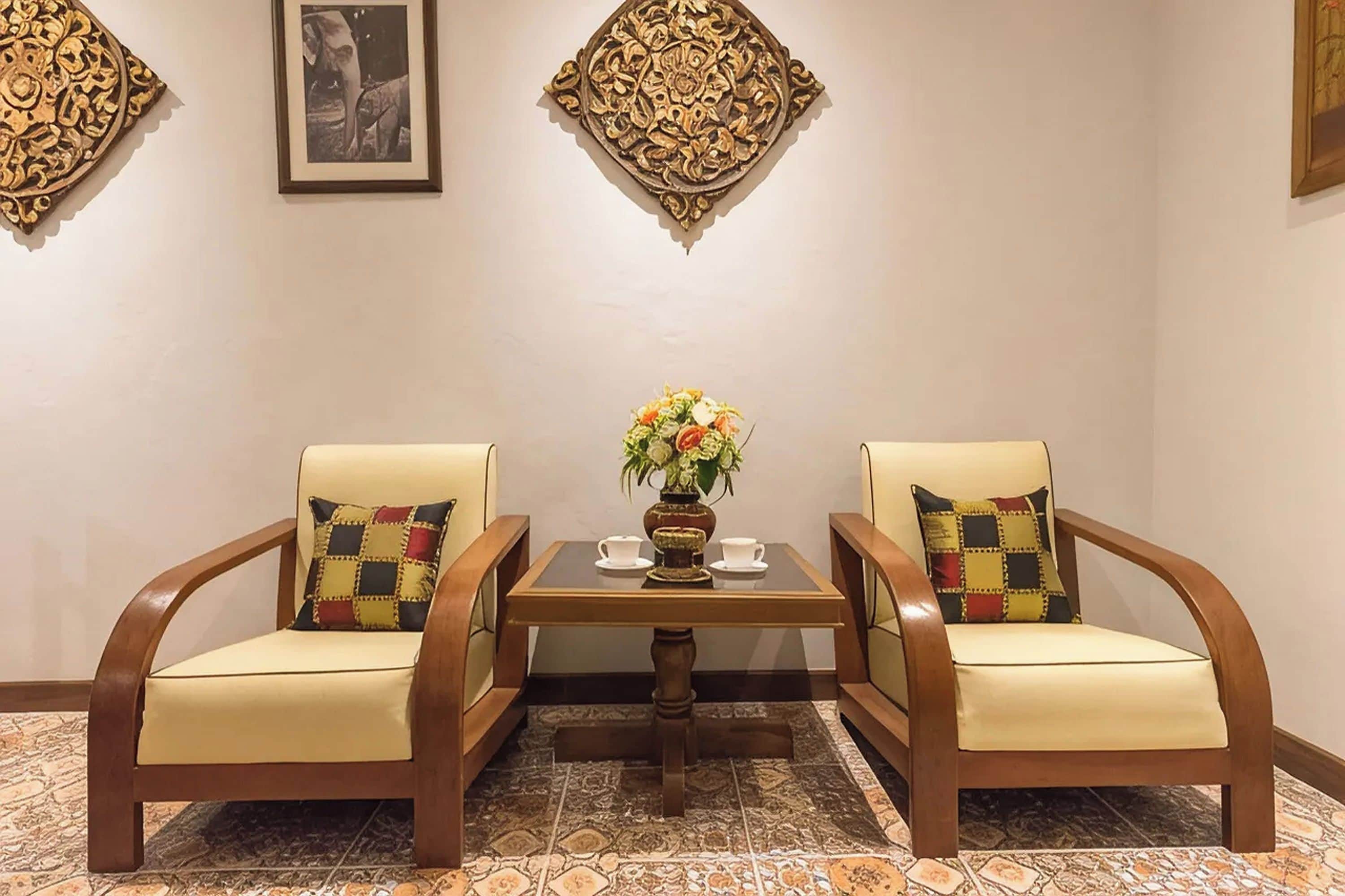 Quarto com duas poltronas, uma mesinha com um vaso de flores e um quadro na parede.