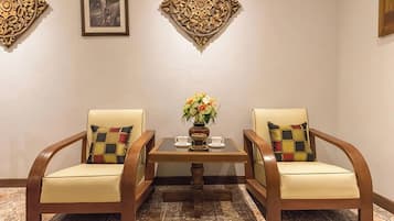 Quarto com duas poltronas, uma mesinha com um vaso de flores e um quadro na parede.