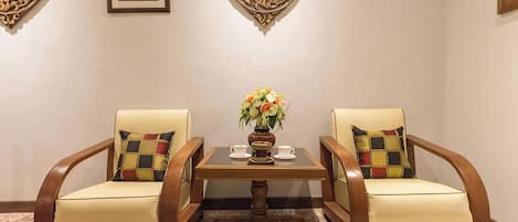 Quarto com duas poltronas, uma mesinha com um vaso de flores e um quadro na parede.